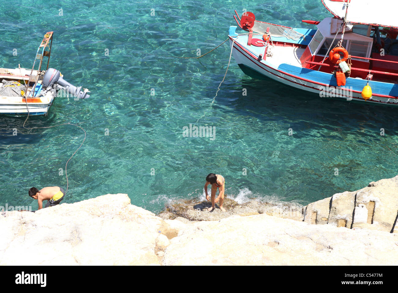 Two boys playing near the ocean on rocks in Crete Stock Photo - Alamy