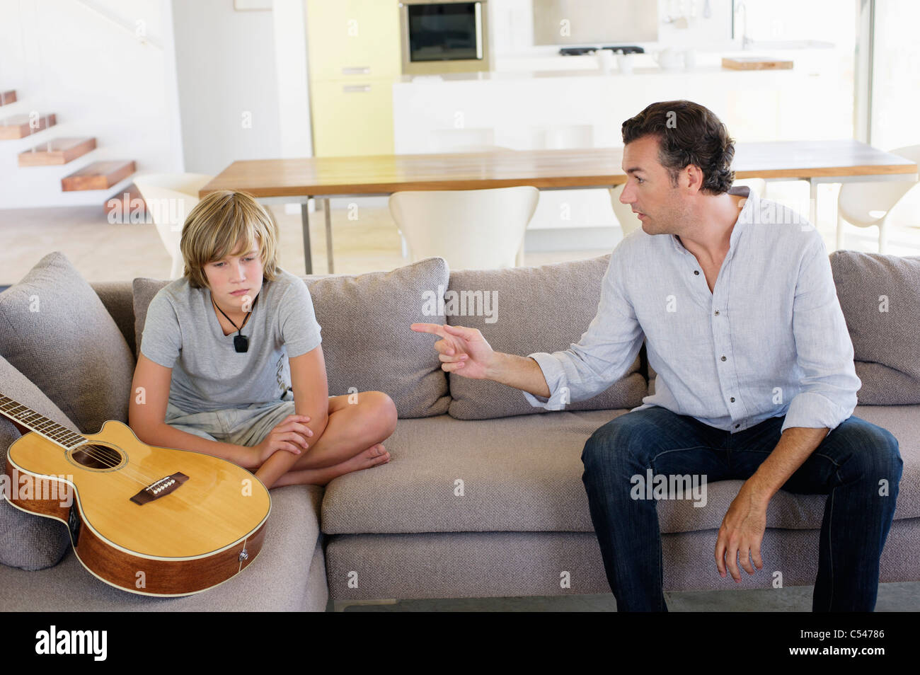 Father complaining to teenage boy sitting with guitar at home Stock ...