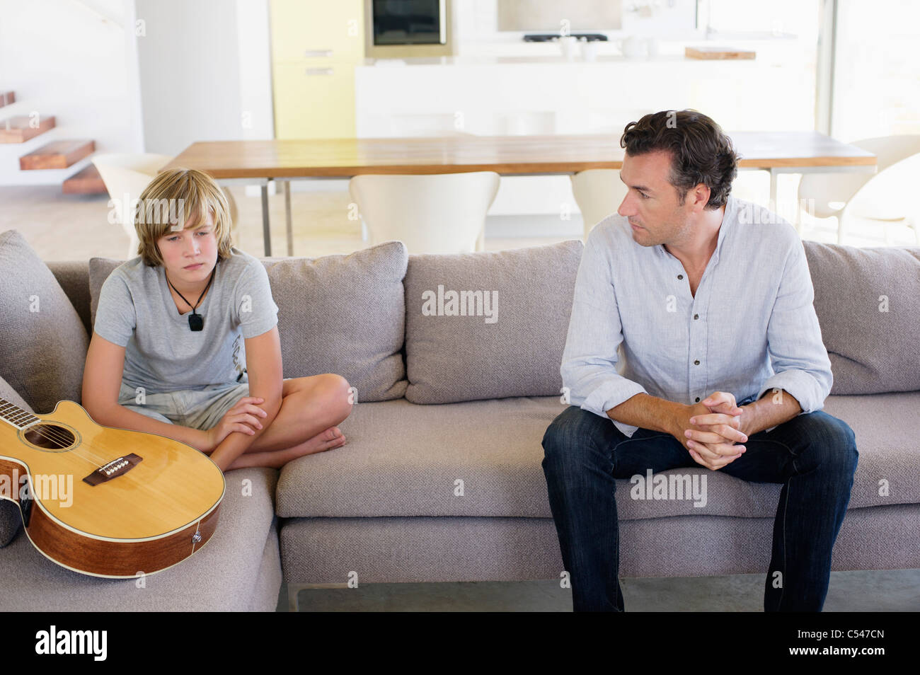 Father complaining to teenage boy sitting with a guitar at home Stock ...