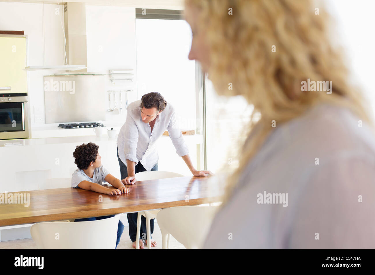 Close-up of a woman with focus on father and son talking to each other ...