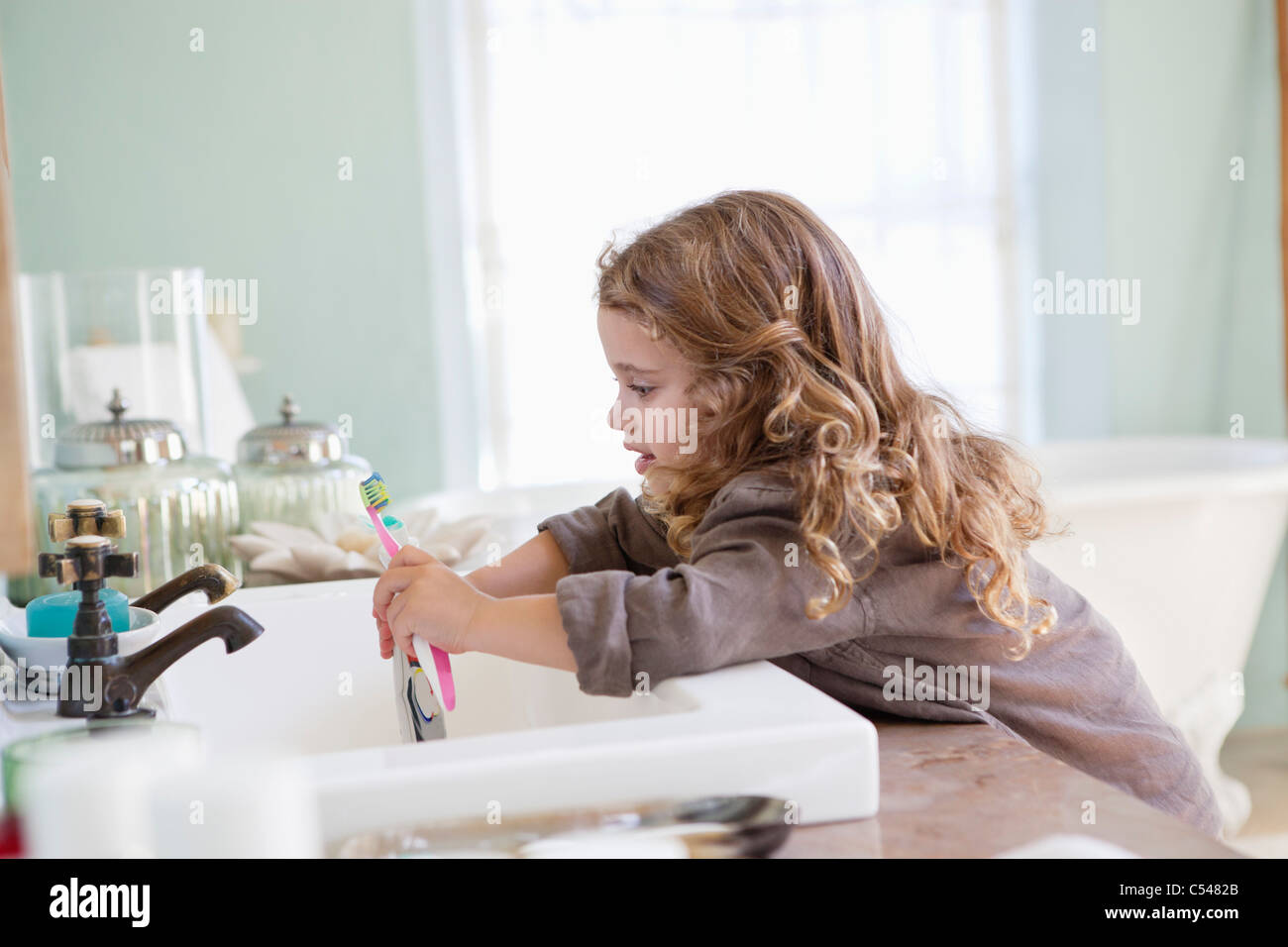Cute little girl brushing teeth at bathroom sink Stock Photo - Alamy