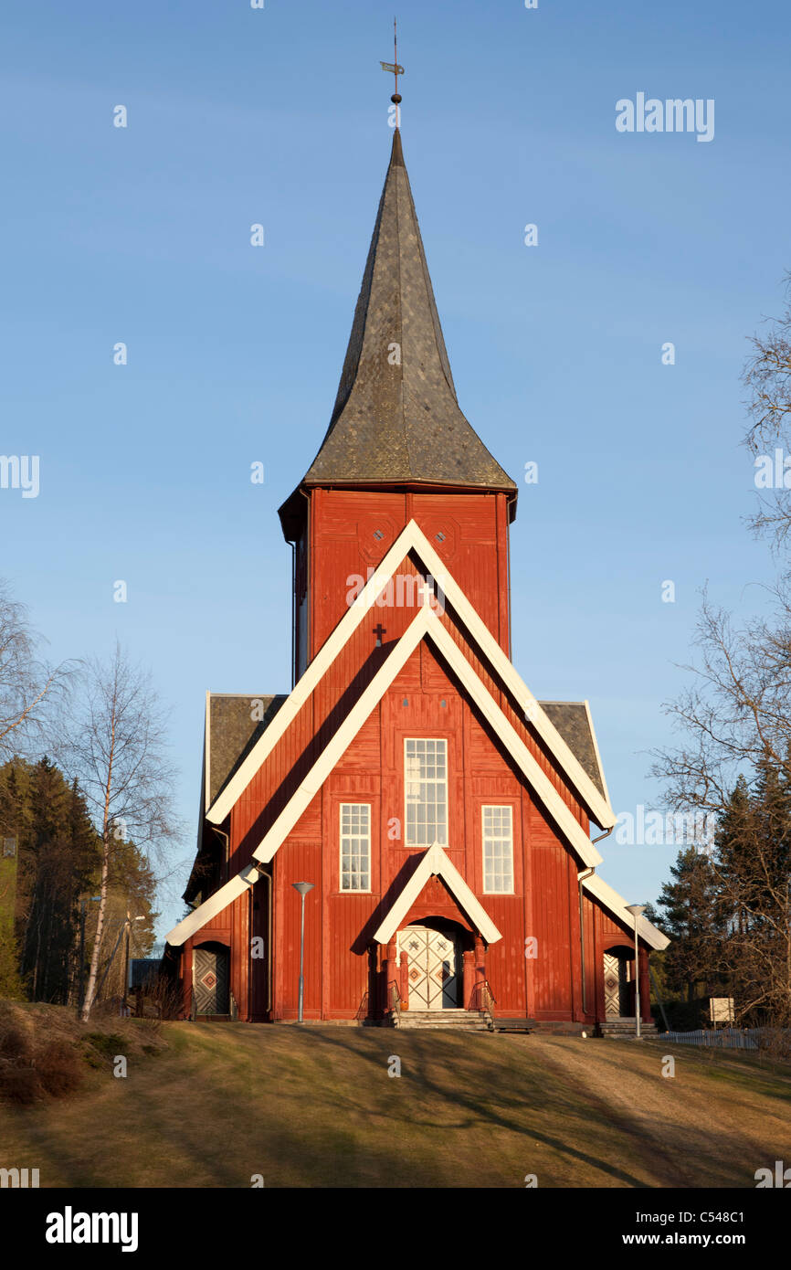A red wooden church surrounded by a forest captures the remaining sun ...