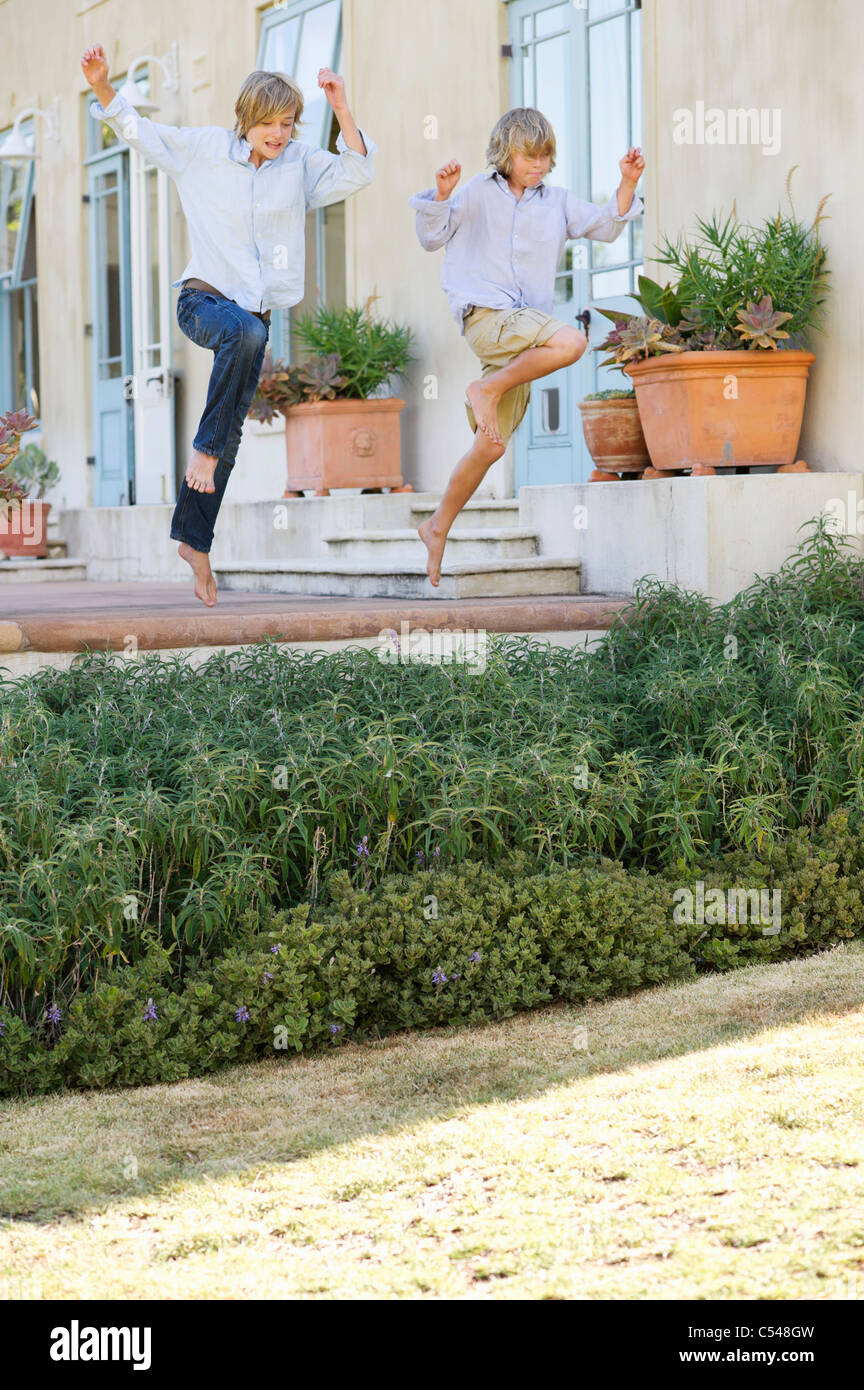 Two little children jumping in air against house Stock Photo - Alamy