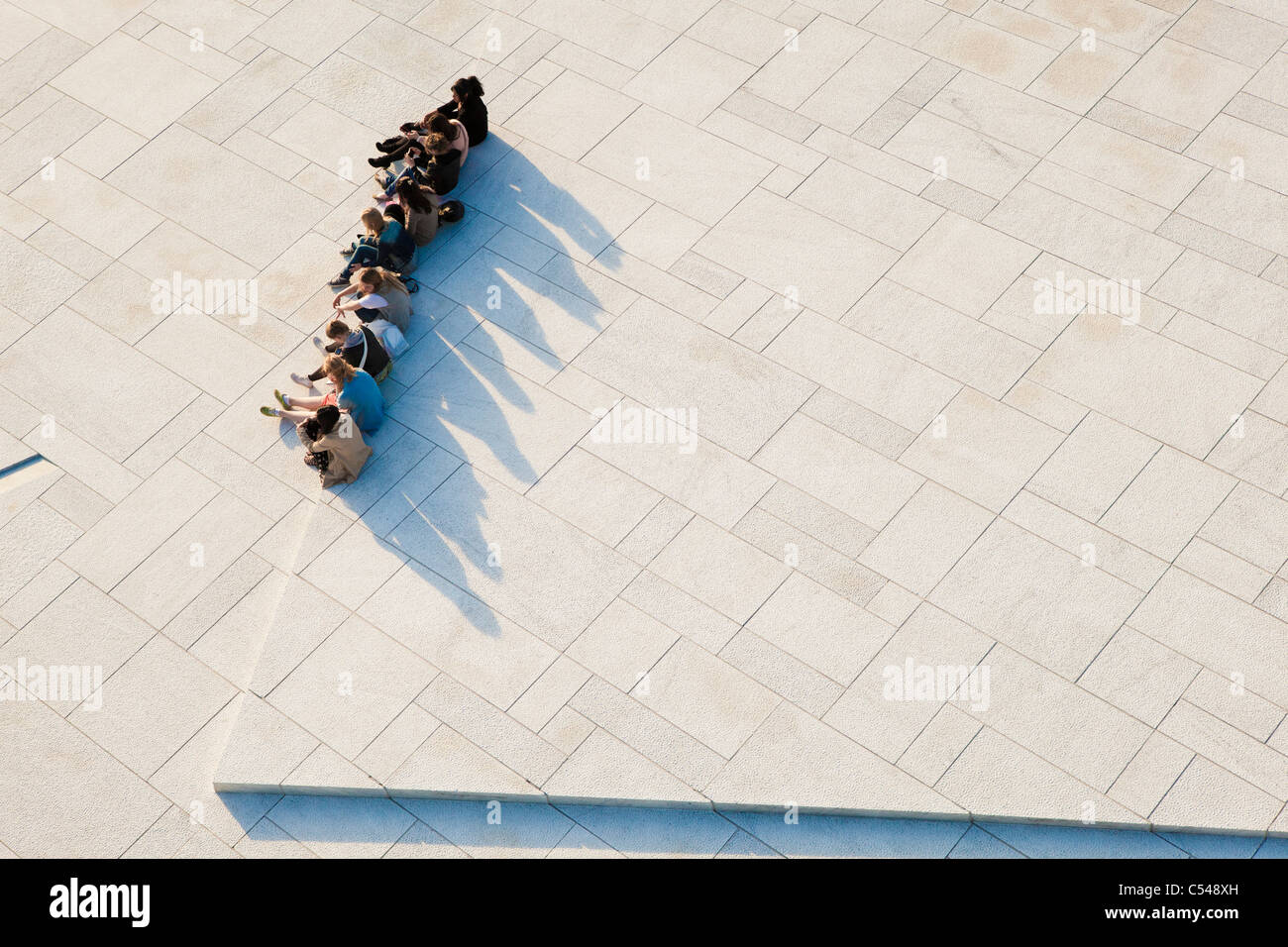 People sitting on a platform at town's square Stock Photo - Alamy