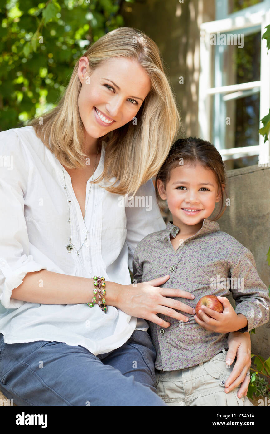 Daughter holding apple with mother smiling Stock Photo - Alamy