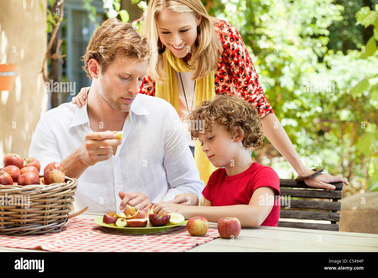 Mother and father watching son cutting apples Stock Photo - Alamy