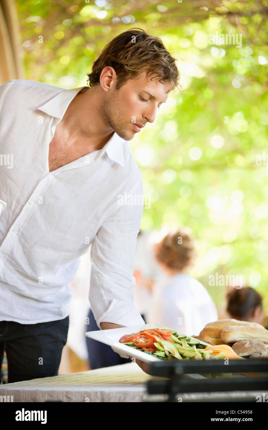 Young man serving salad Stock Photo - Alamy