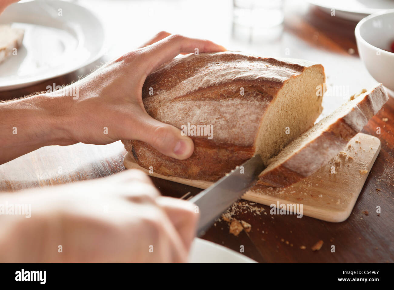 Close-up of a person's hand cutting bread Stock Photo - Alamy