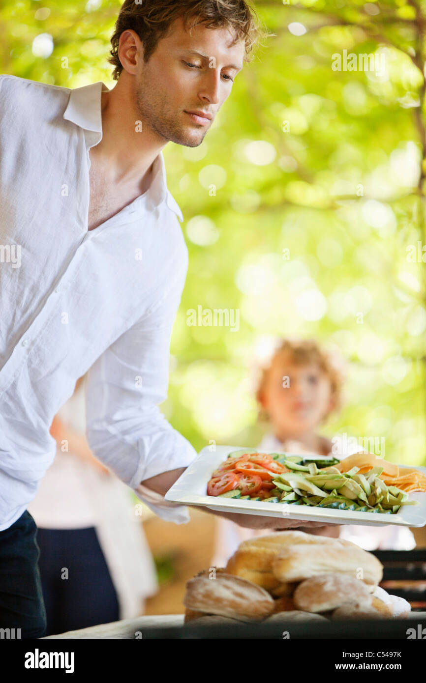 Young man serving salad Stock Photo - Alamy