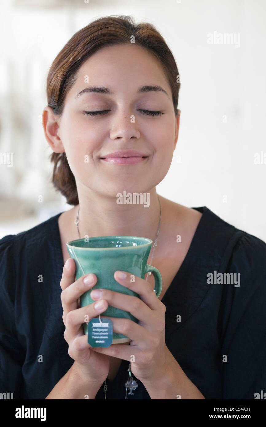 Young woman holding cup of tea with her eyes closed Stock Photo - Alamy