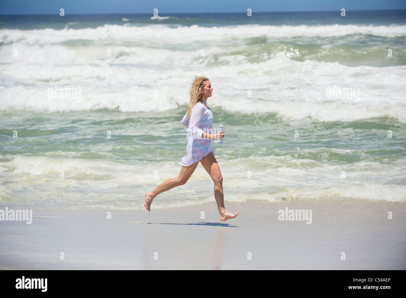 Side profile of a beautiful woman running on the beach Stock Photo - Alamy
