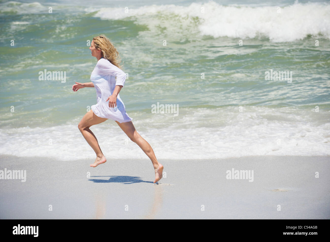 Side profile of a beautiful woman running on the beach Stock Photo - Alamy