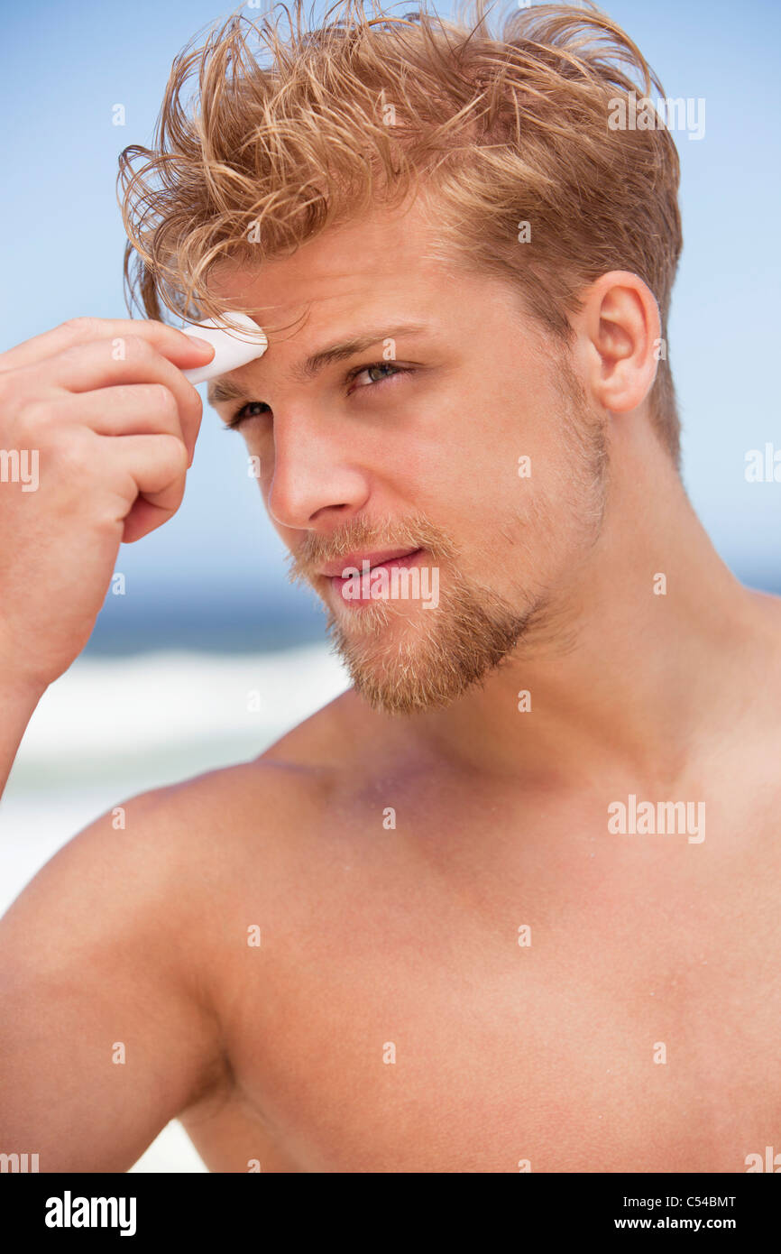 Young man applying moisturizer on his face Stock Photo - Alamy