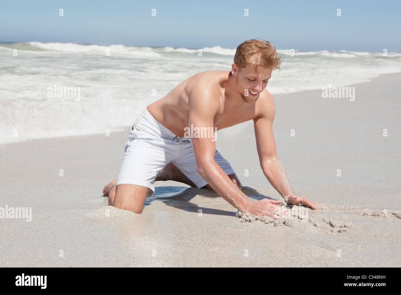 Man playing with sand on beach Stock Photo - Alamy