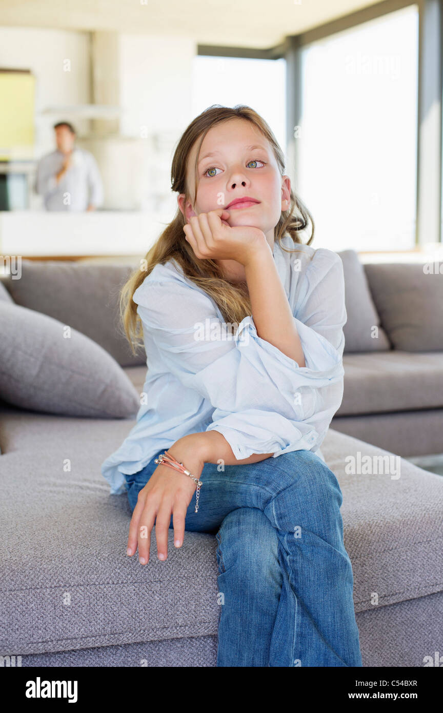Girl sitting on a couch and thinking Stock Photo - Alamy