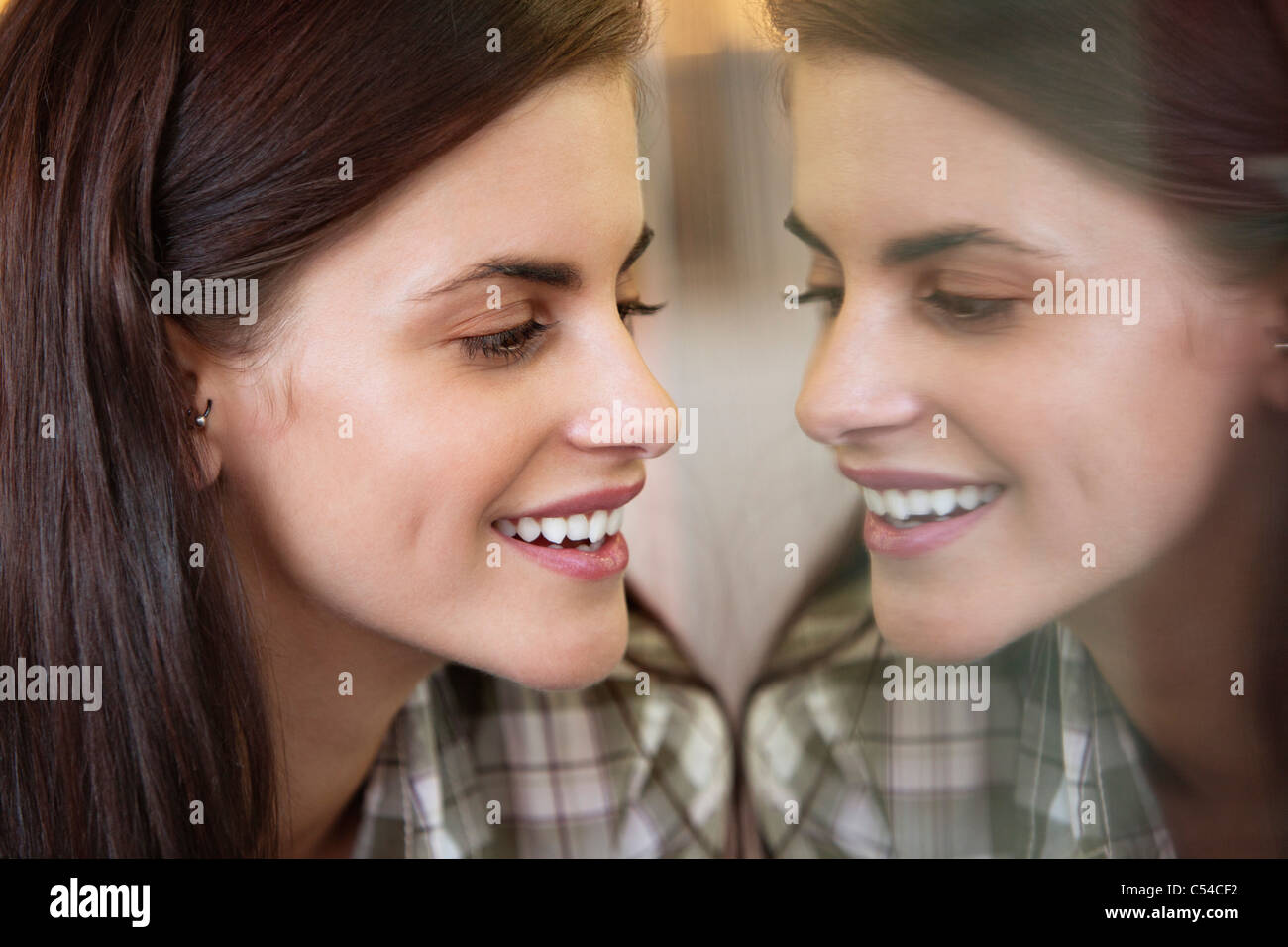 Smiling woman looking at her own reflection in the mirror Stock Photo ...