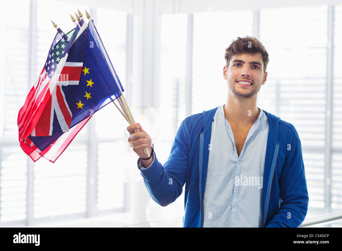 Portrait of a man holding flags of various countries at an airport ...