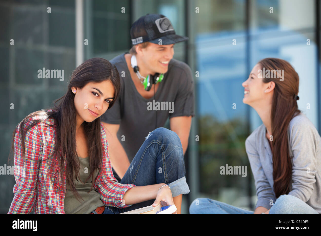 Portrait of a woman sitting with her friends looking at each other ...