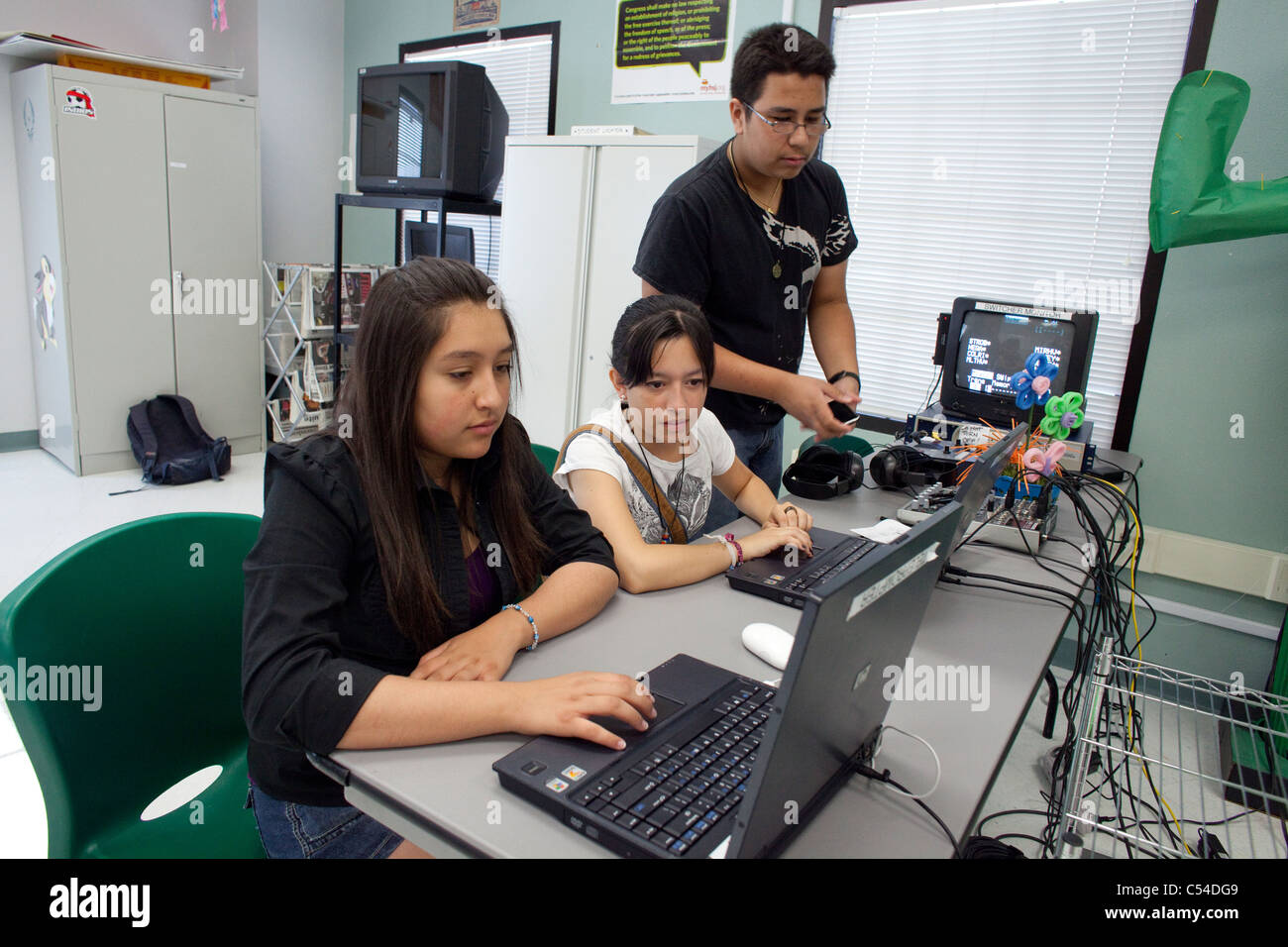 Female Hispanic students use laptop computers as male Hispanic teacher ...