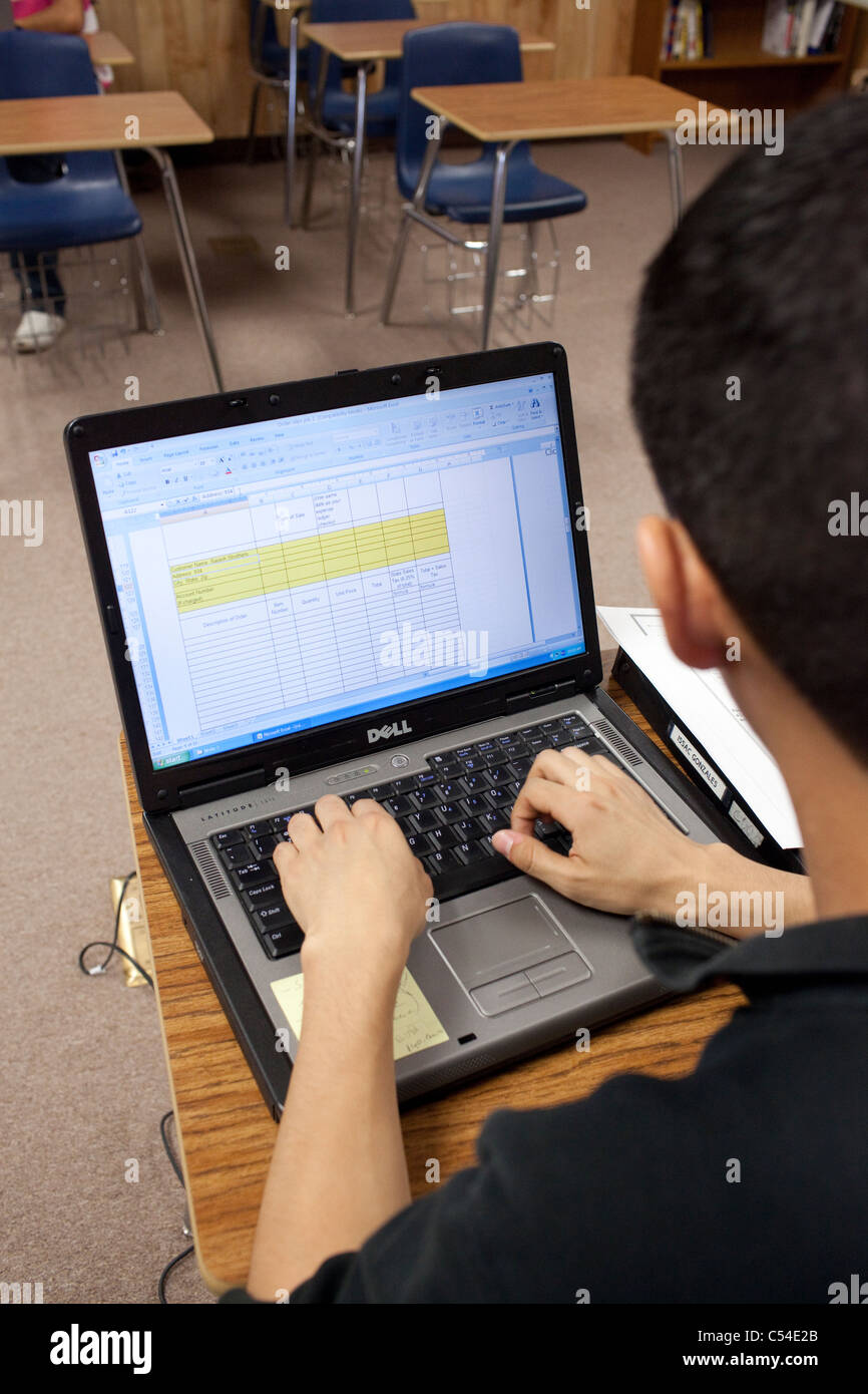 Hispanic male student uses laptop computer to do school work inside ...