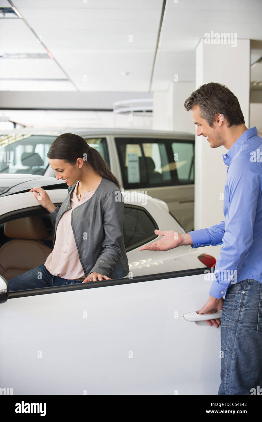Young woman checking car from inside while man holding the door Stock ...