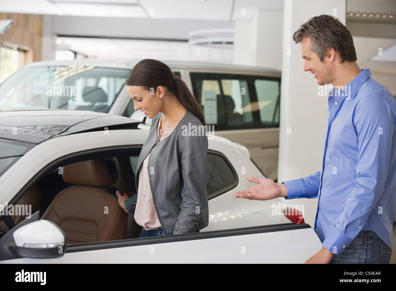 Young woman checking car from inside while man holding the door Stock ...