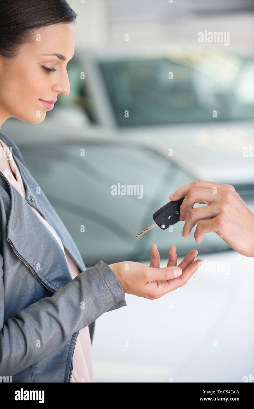 Side profile of a young woman taking car key in showroom Stock Photo ...