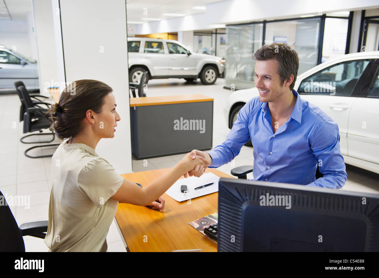 Saleswoman shaking hands with her customer Stock Photo - Alamy