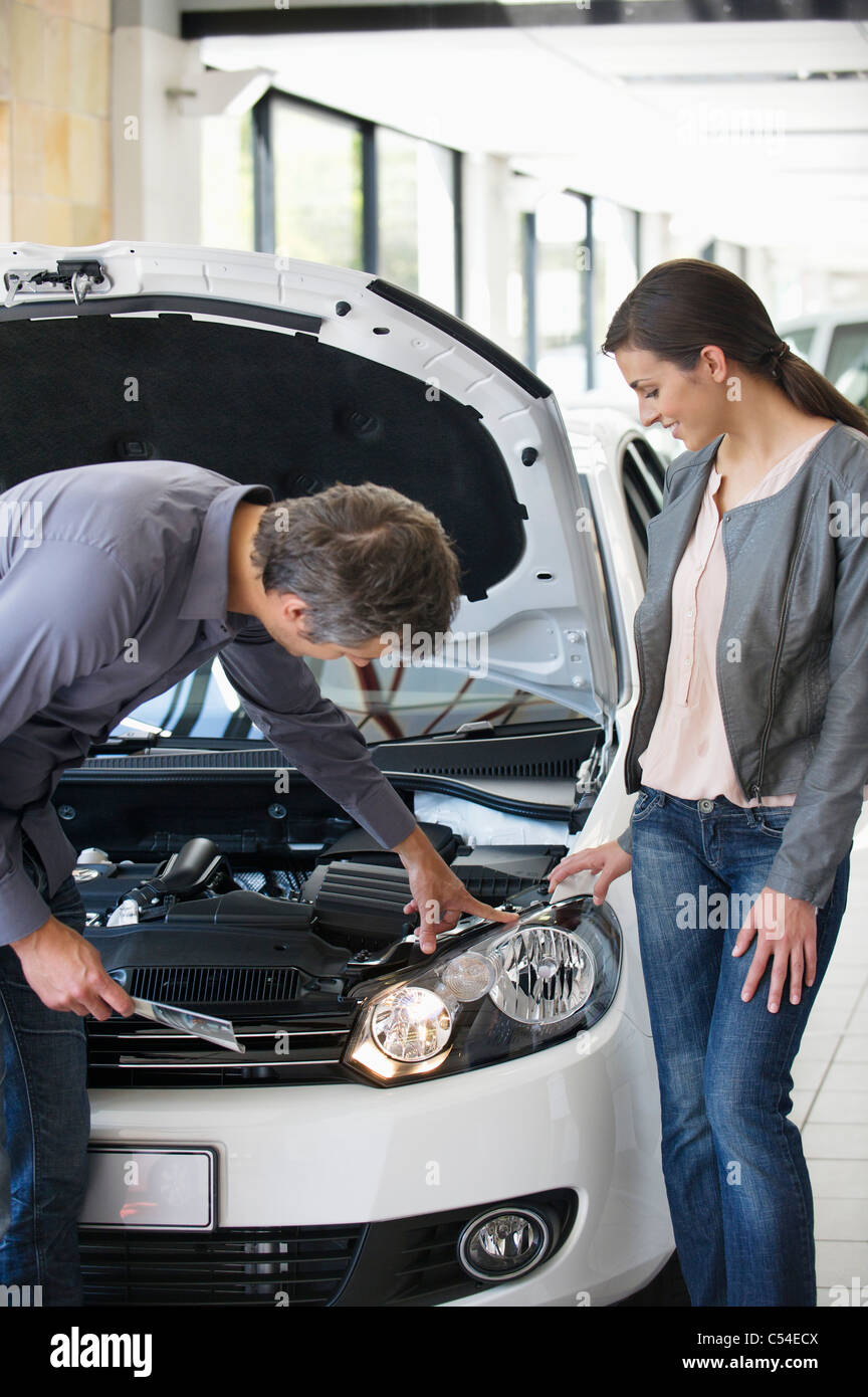 Couple looking at a car engine in a showroom Stock Photo - Alamy