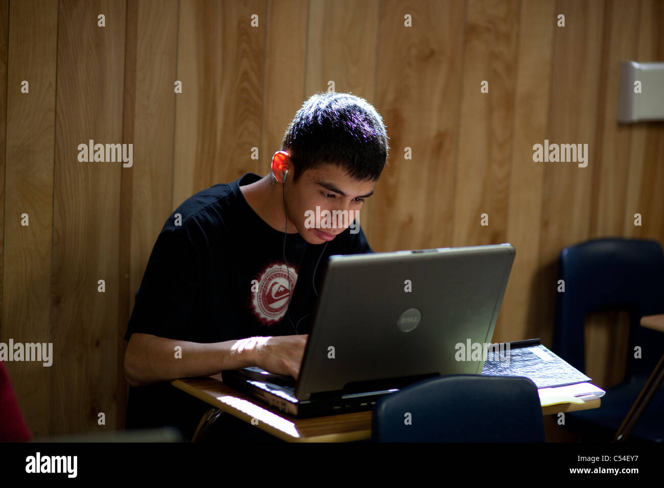 Hispanic male high school student works alone on laptop computer in El ...