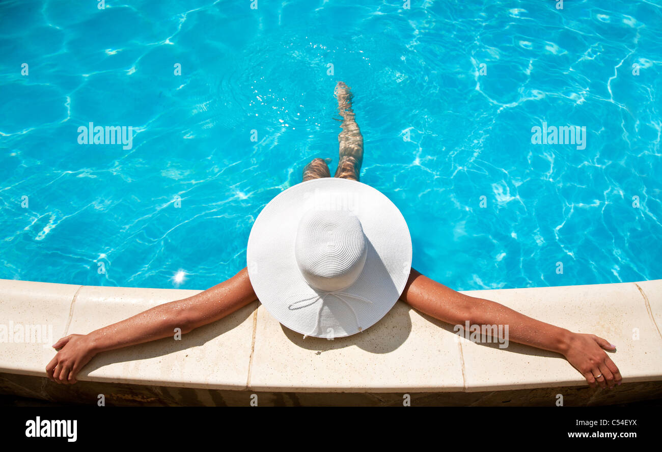 Young woman sitting on the ledge of the pool Stock Photo - Alamy
