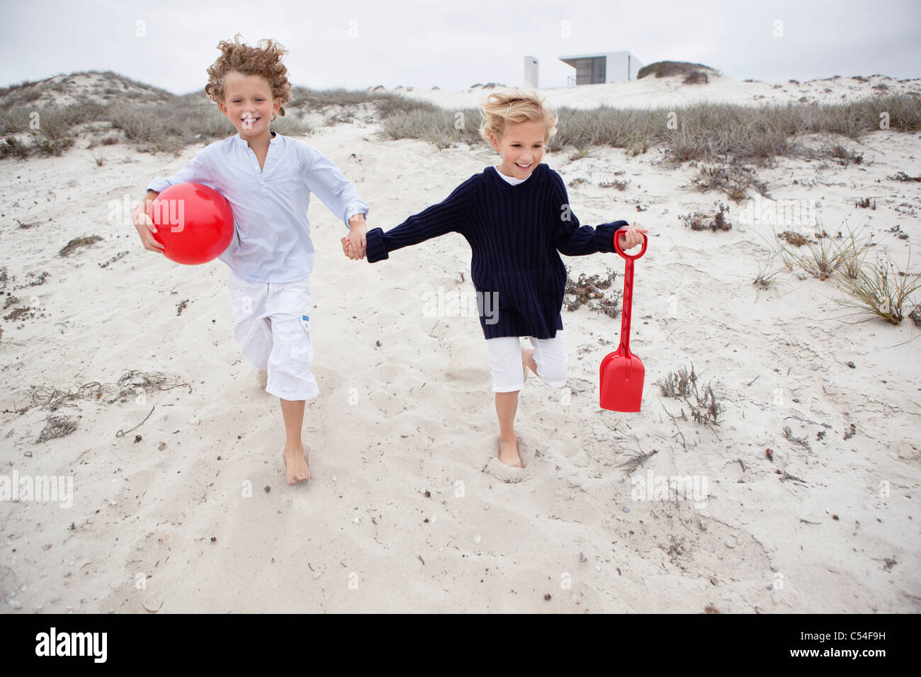 Children holding toys and running on sand Stock Photo - Alamy