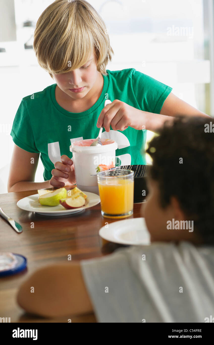 Teenage boy having breakfast with his brother sitting in front of him ...