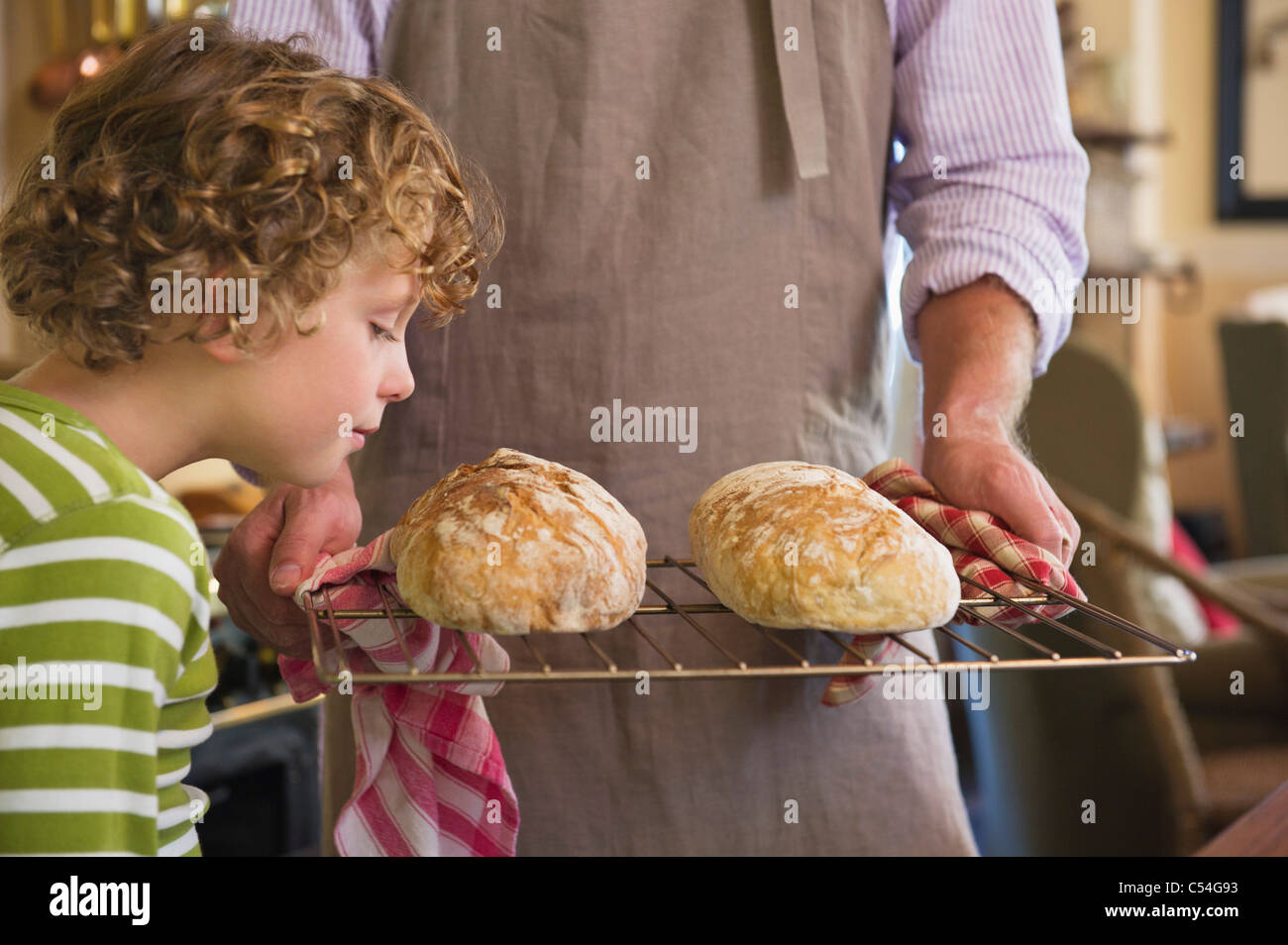 Cute little boy smelling baked bread in father's hand Stock Photo - Alamy