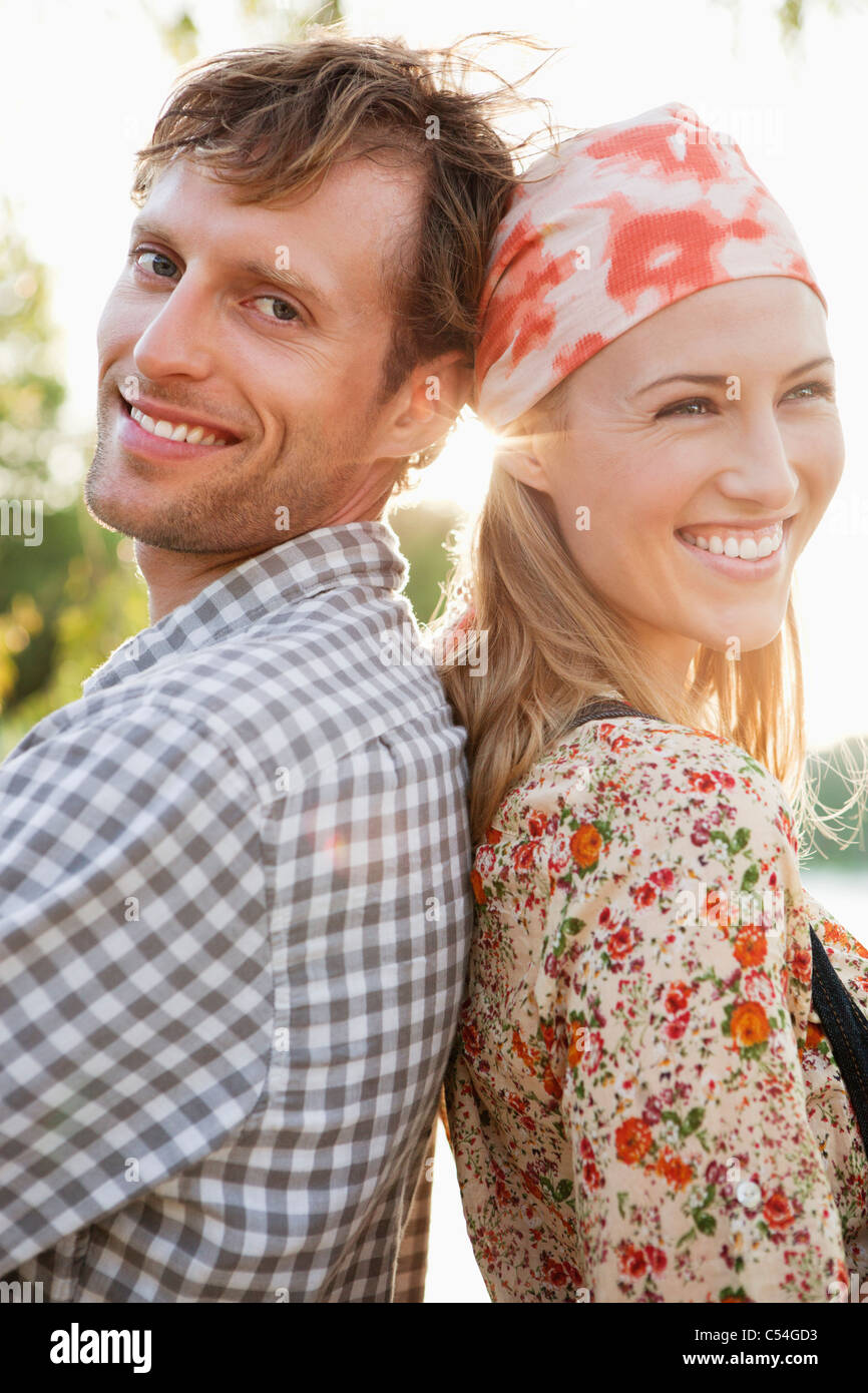 Portrait of a couple standing back to back and smiling Stock Photo - Alamy