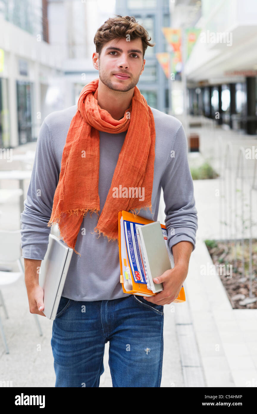 Portrait of a man walking with books and a laptop in hands Stock Photo ...