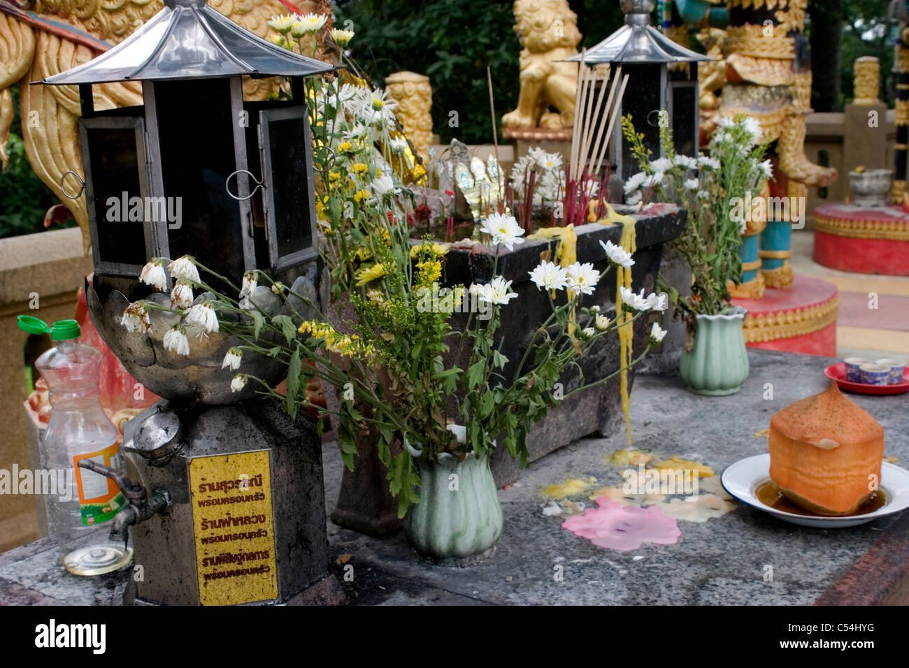 Flowers, lanterns and other objects form an outdoor altar display at a ...