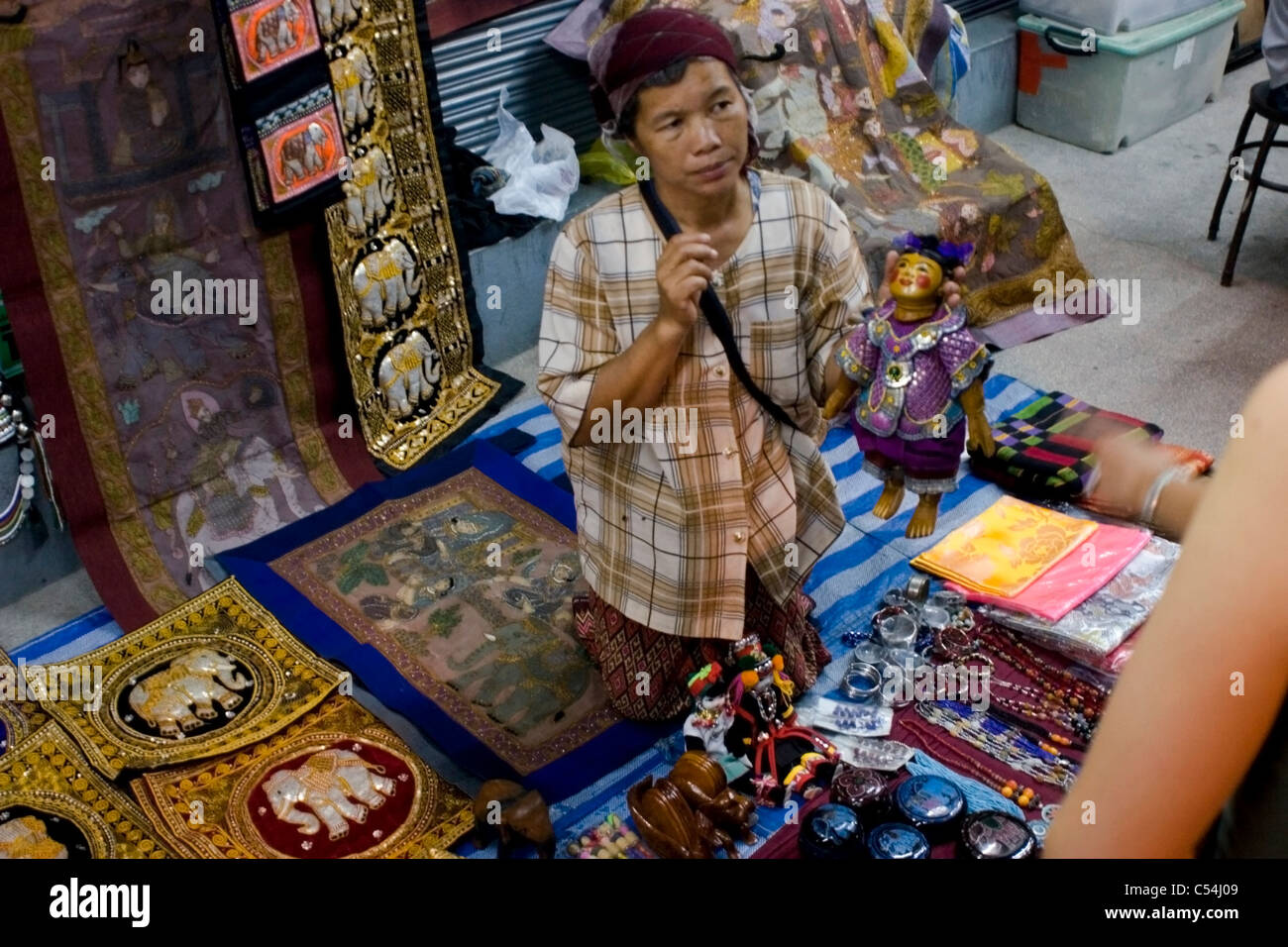 A man is selling colorful rugs and other souvenir items to tourists on ...