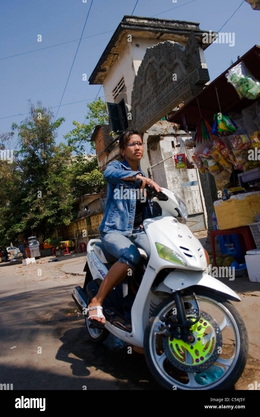A young Asian woman is riding a modern motorcycle on a city street in ...