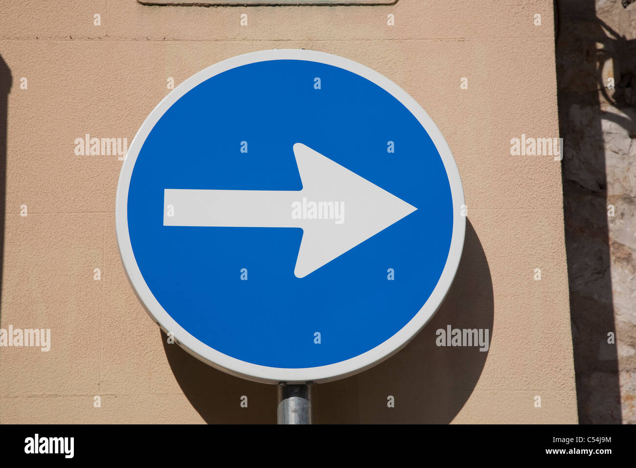 Blue Arrow One Way Sign against Pale Wall Stock Photo - Alamy