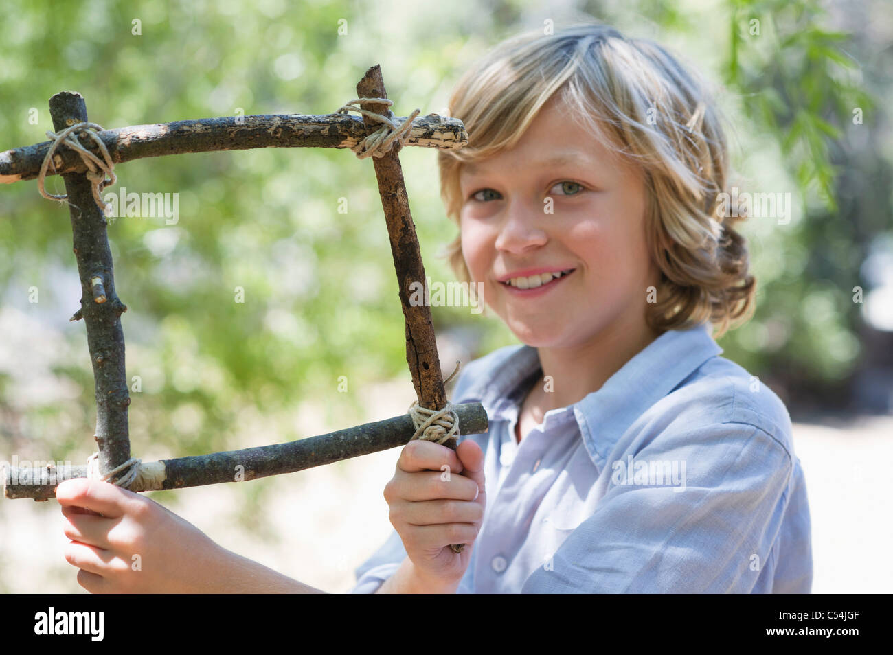 Portrait of a cute little boy holding frame of driftwood outdoors Stock ...