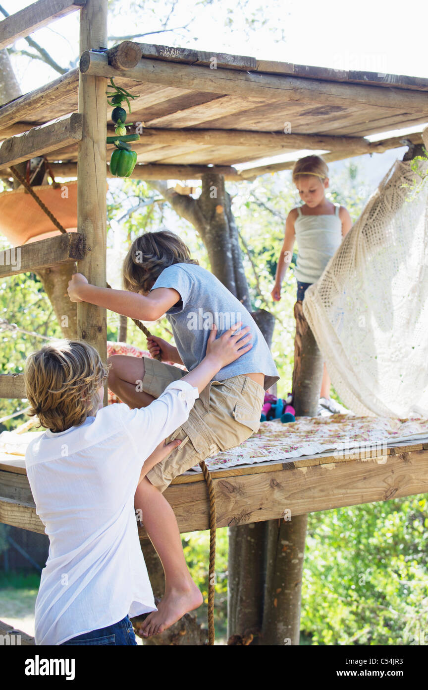 Rear view of a boy grasping rope to reach tree house Stock Photo - Alamy