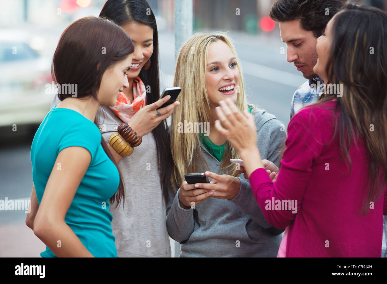 Friends using mobile phones outdoors Stock Photo - Alamy