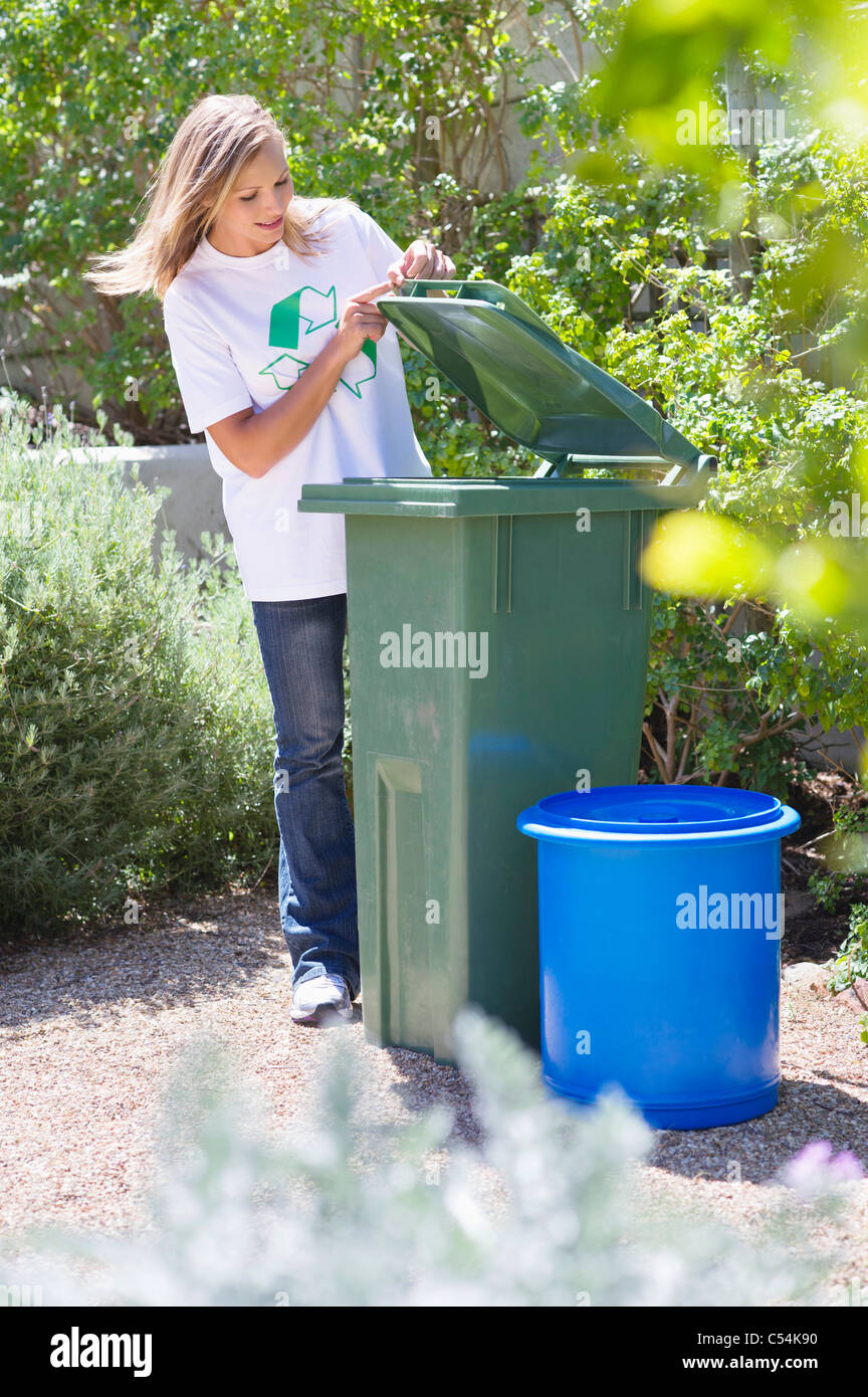 Woman looking into recycling bin Stock Photo - Alamy