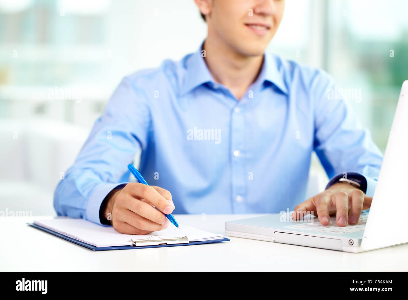 Image of successful businessman typing and making notes Stock Photo - Alamy