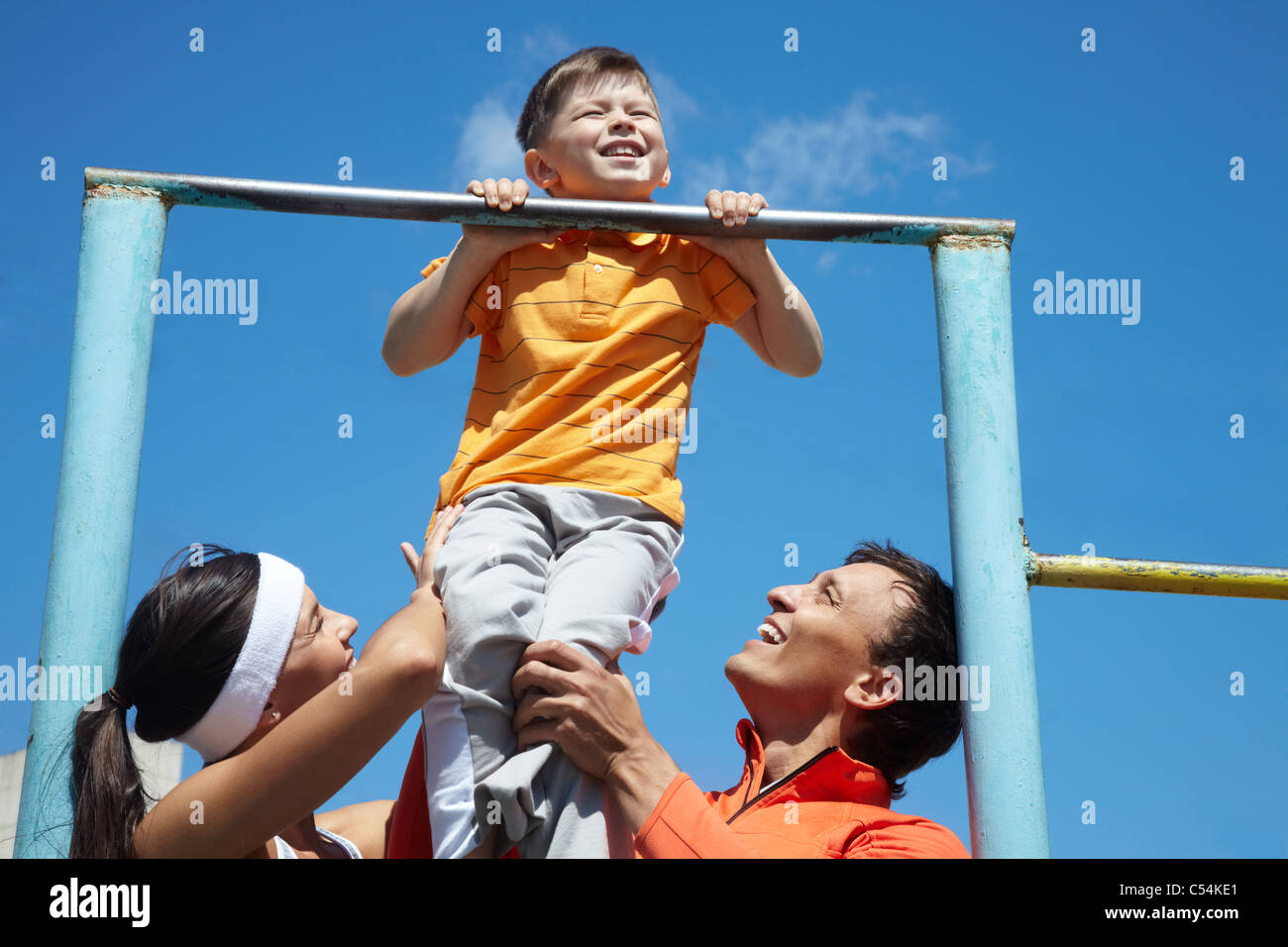 Image of happy parents helping their son to do physical exercise Stock ...