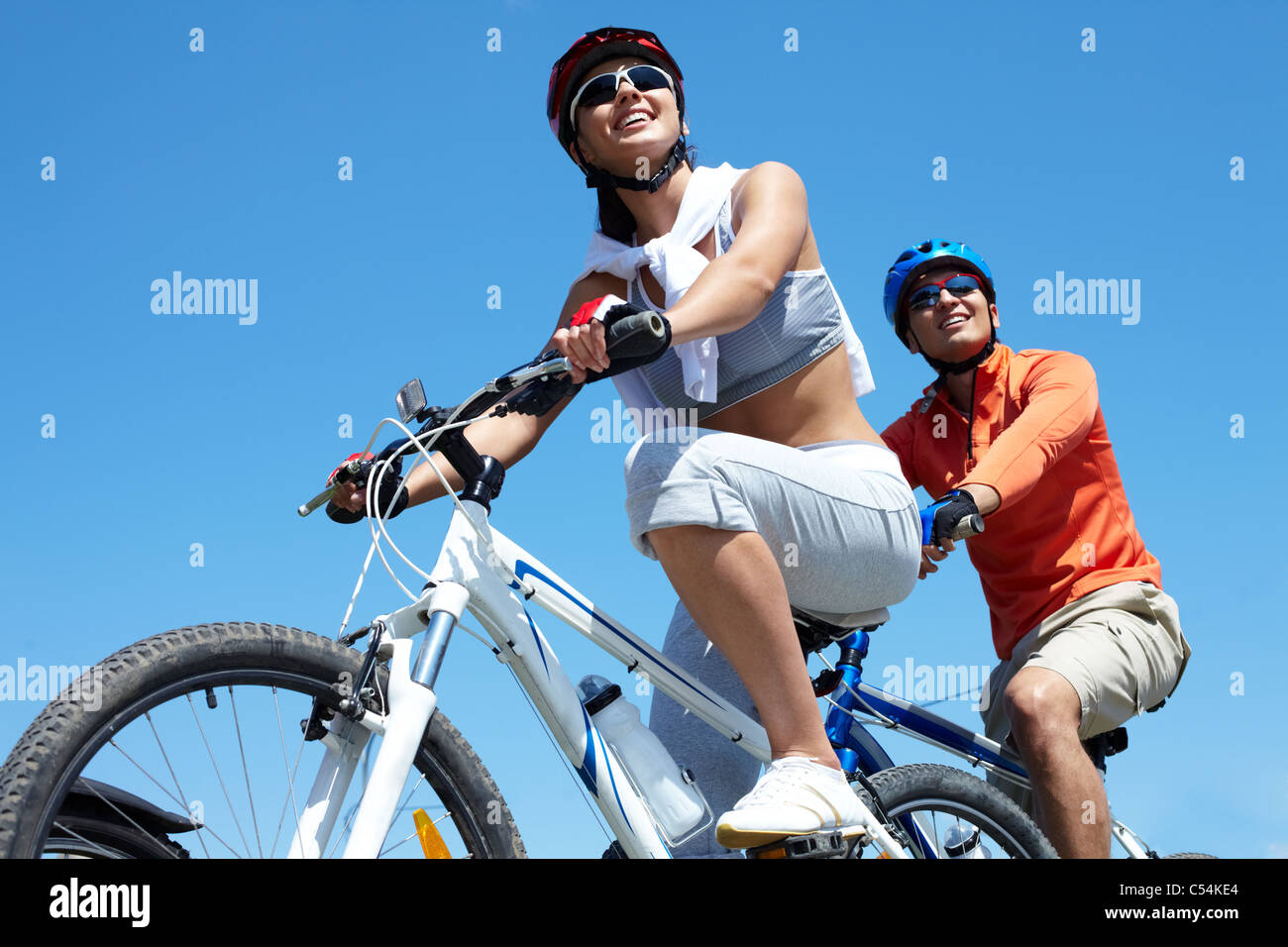 A young couple racing on bicycles against blue sky Stock Photo - Alamy