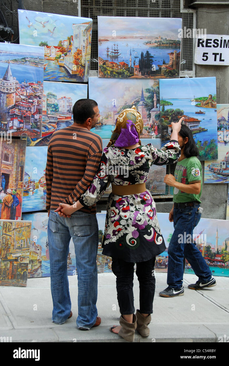 ISTANBUL, TURKEY. A young Turkish couple looking at paintings for sale ...