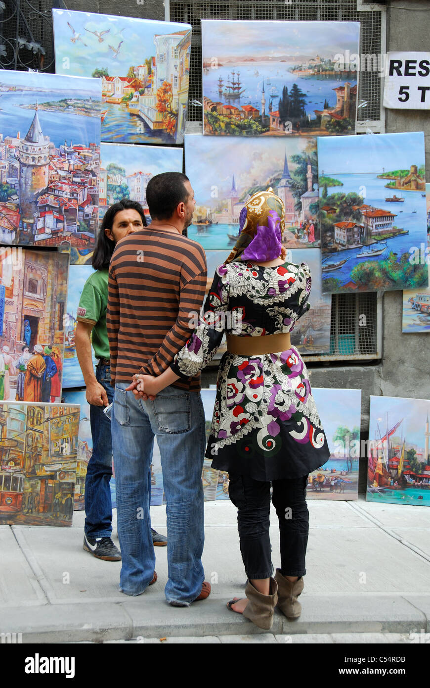 ISTANBUL, TURKEY. A young Turkish couple looking at paintings for sale ...
