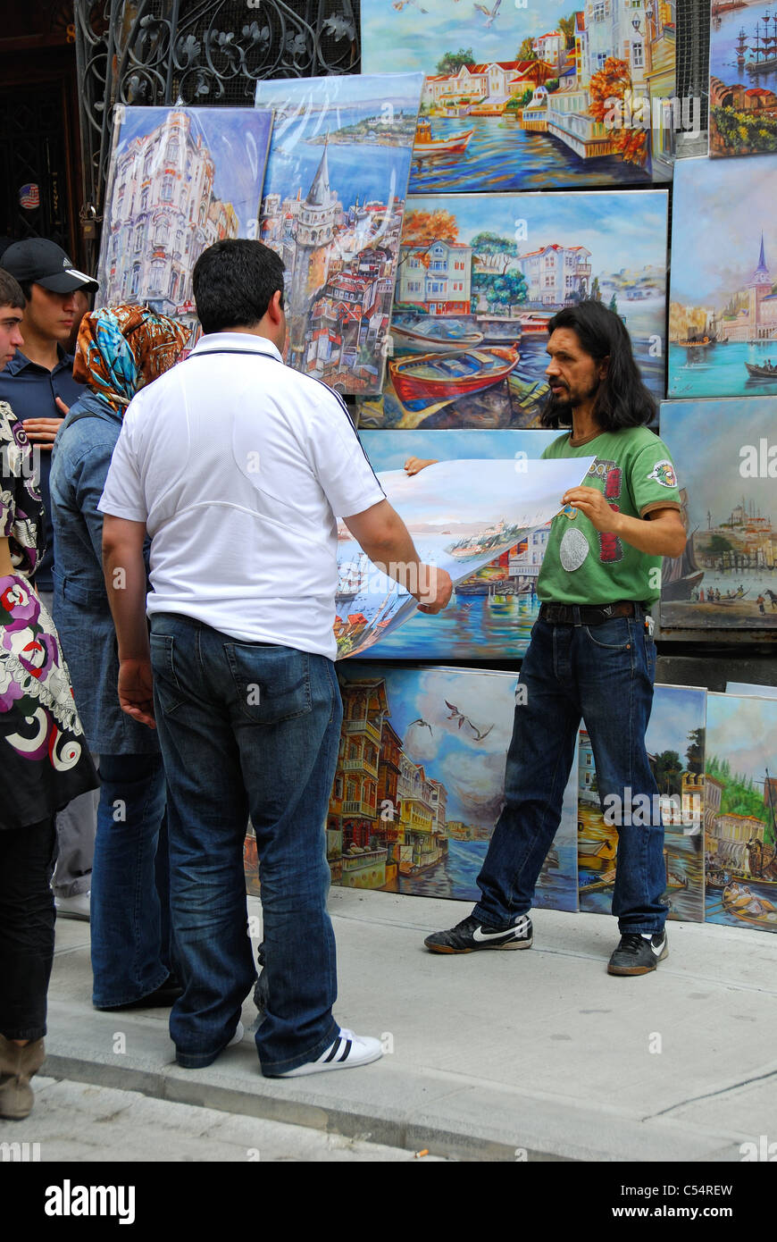 ISTANBUL, TURKEY. An artist showing his paintings to customers on ...